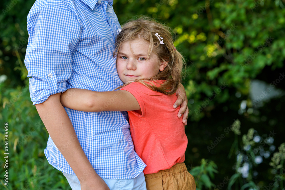An upset little girl finds comfort in the embrace of her caring teenage ...