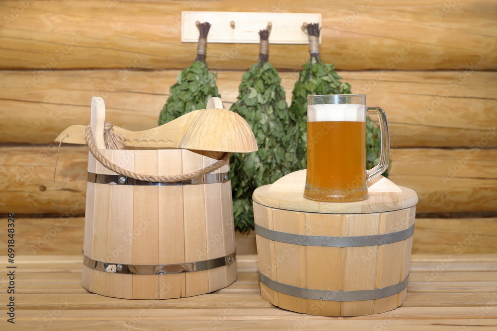 A glass mug of light beer stands on cover of a wooden vat, standing ...