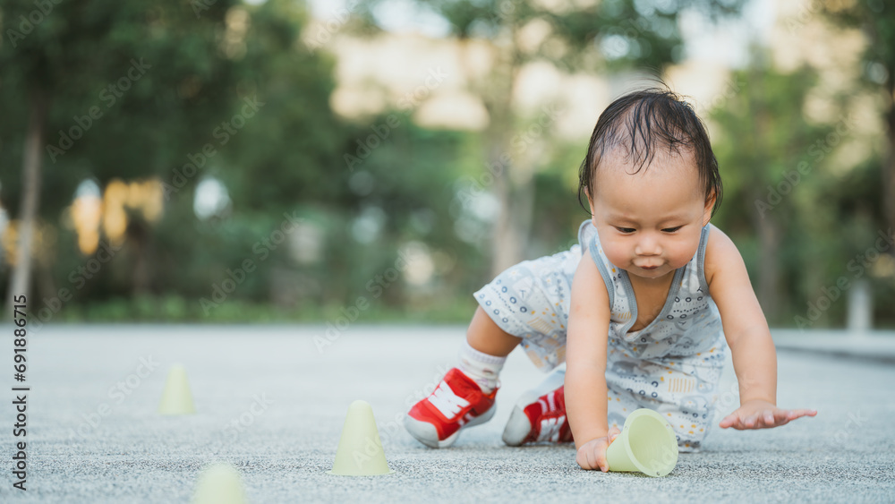Toddler boy playing with yellow cone marker. Child was about to stand ...