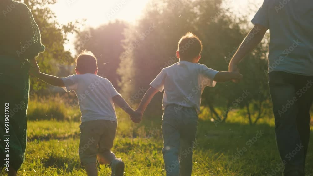 Large family of parents and children runs joining hands across meadow ...