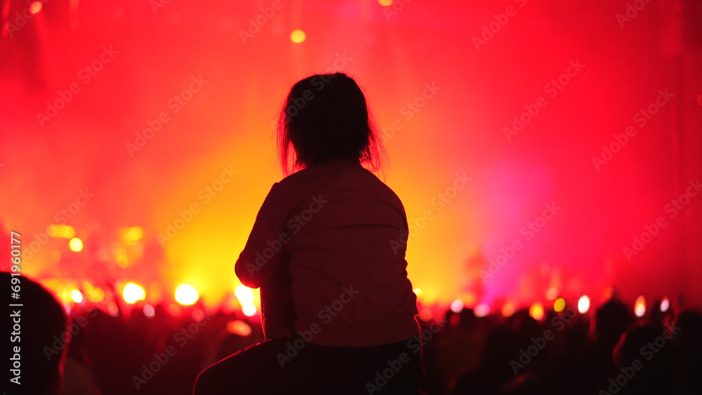 Happy little girl sit on her dad. Small kid have fun live music concert ...