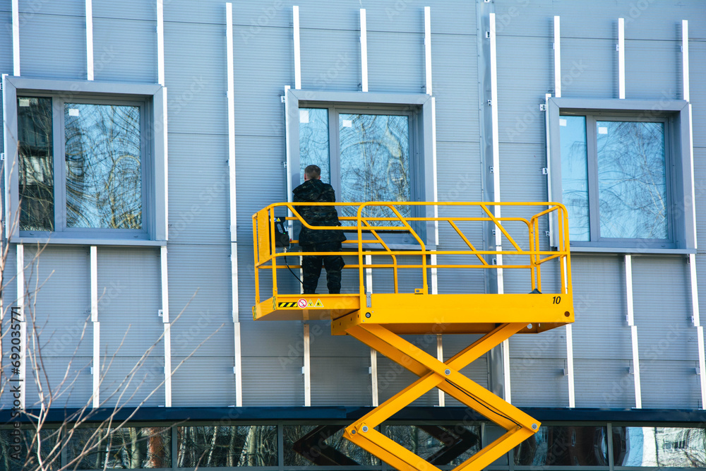 Foto de Construction worker using a scissor lift to install building ...