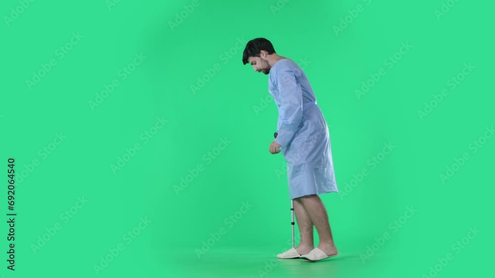 Man in robe making few successful steps with crutch, slowly walking and ...