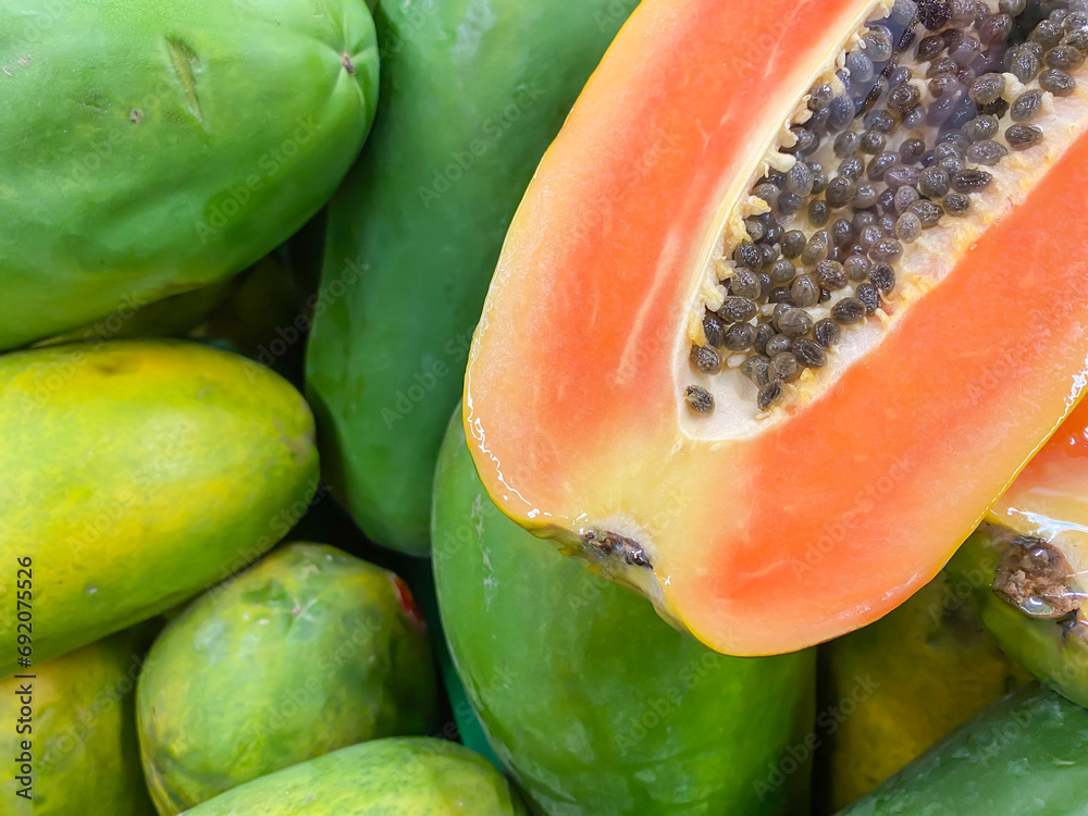 Half sliced fresh papayas with green skin and orange flesh in the ...
