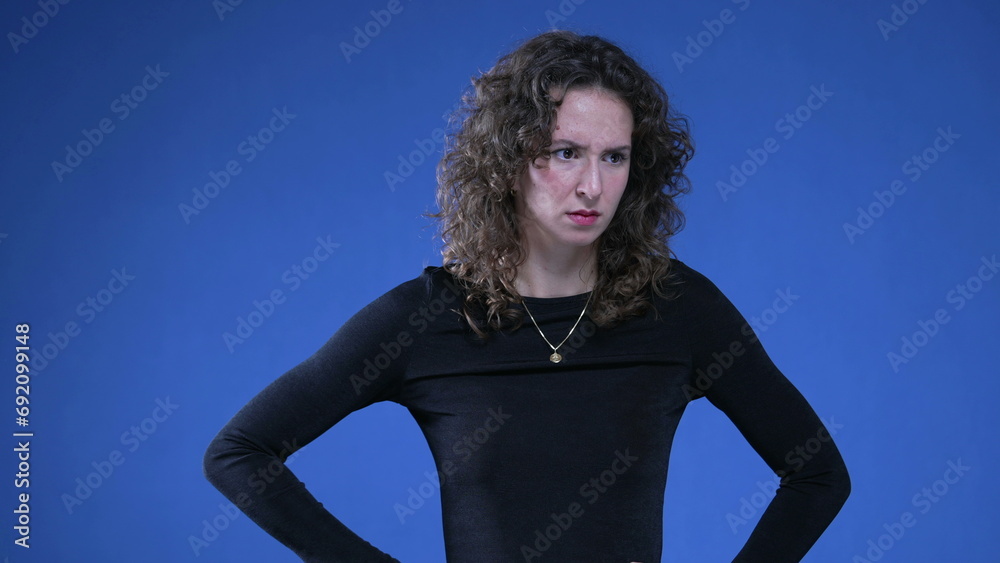 Shocked woman reacting with perplexity on blue background with hands on ...