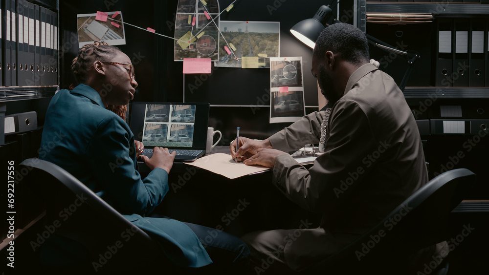 Two police officers analyzing surveillance footage, working on case ...