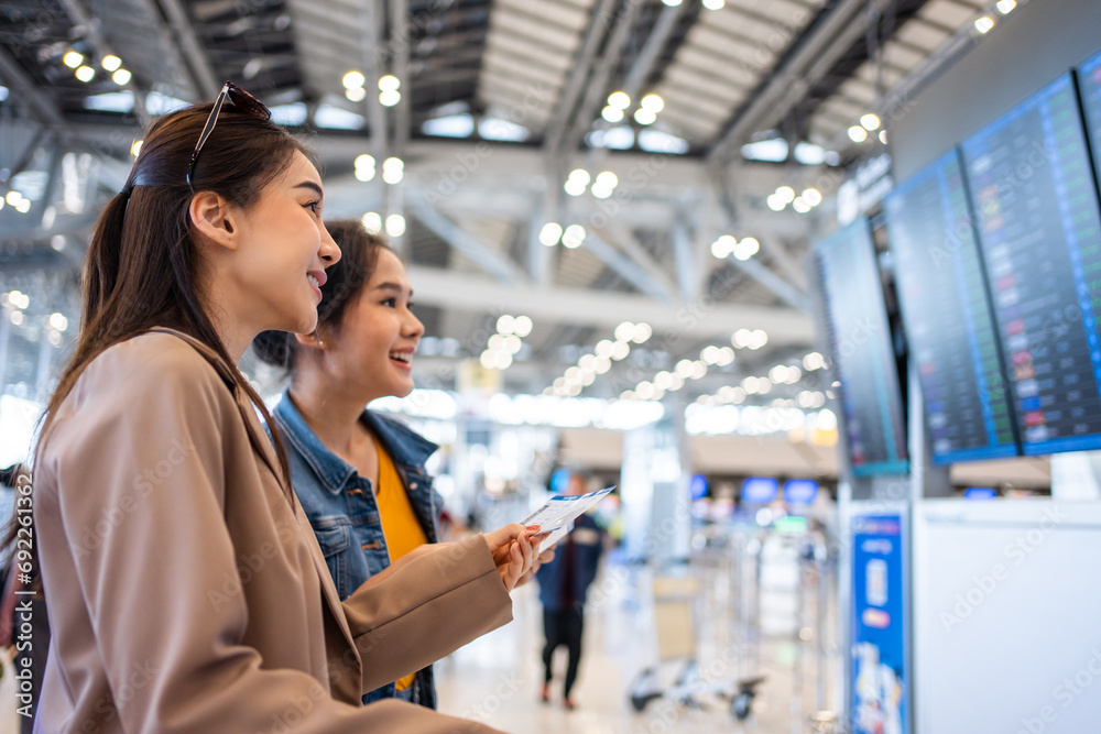 Asian young women passenger checking depature boarding pass in airport ...