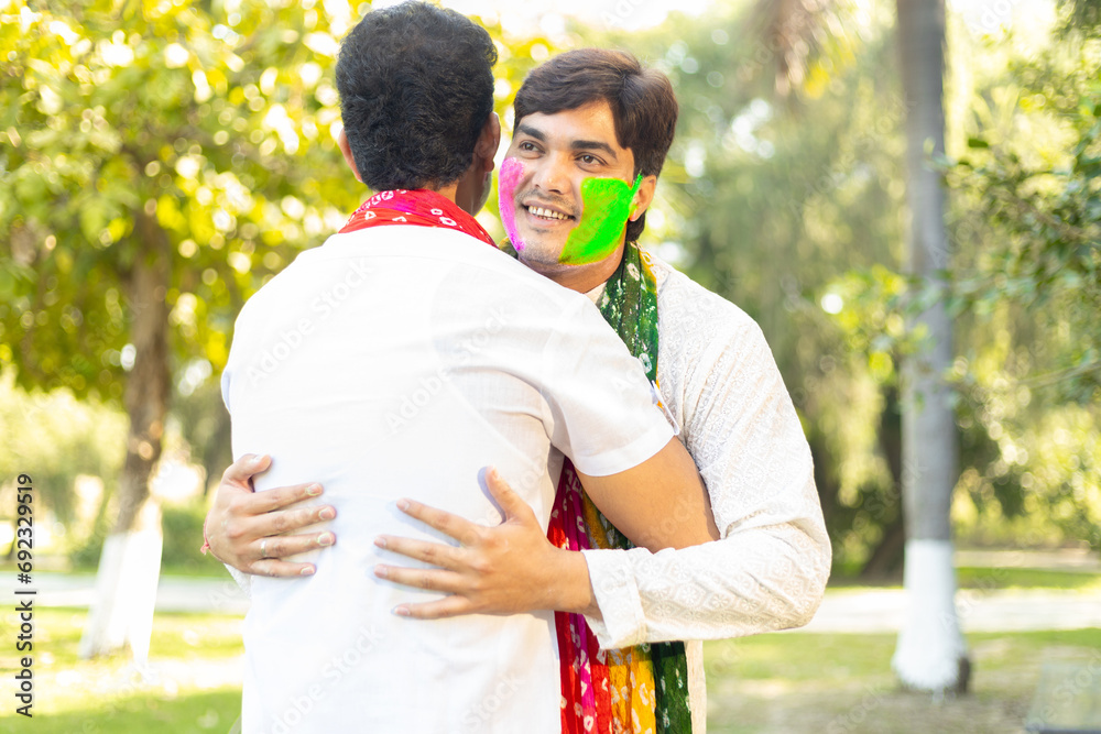 Two young indian men wearing white kurta greeting, hugging each other ...