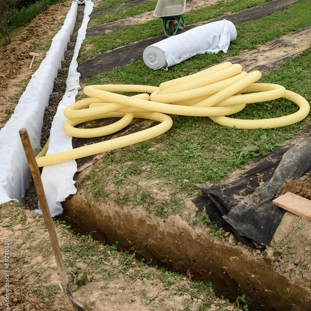 Yellow corrugated pipe with perforation in a trench with crushed stone ...