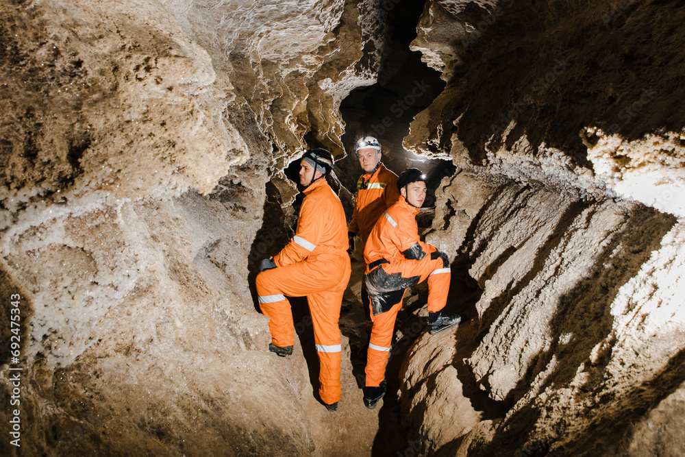 Three men, strong physique, explore the cave. Men dressed in special ...