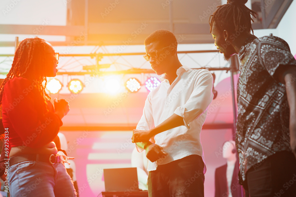 Young couple socializing and dancing in nightclub illuminated with ...