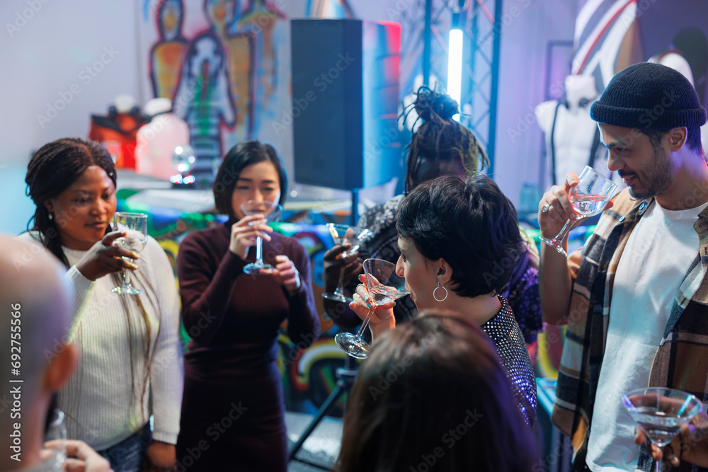 Diverse people crowd drinking alcohol beverages while celebrating in ...