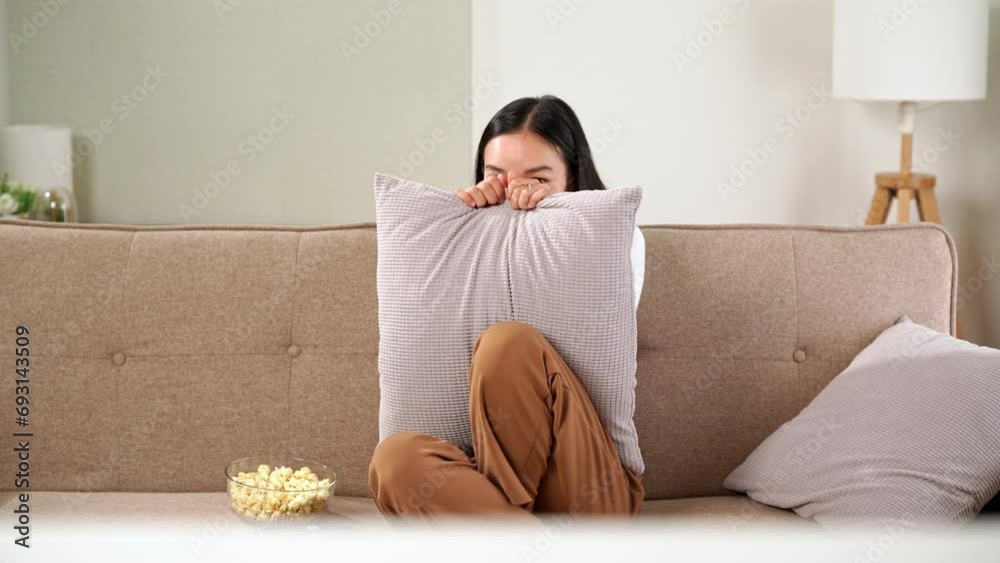 Young asian woman watching scary movie TV on sofa something excited in ...
