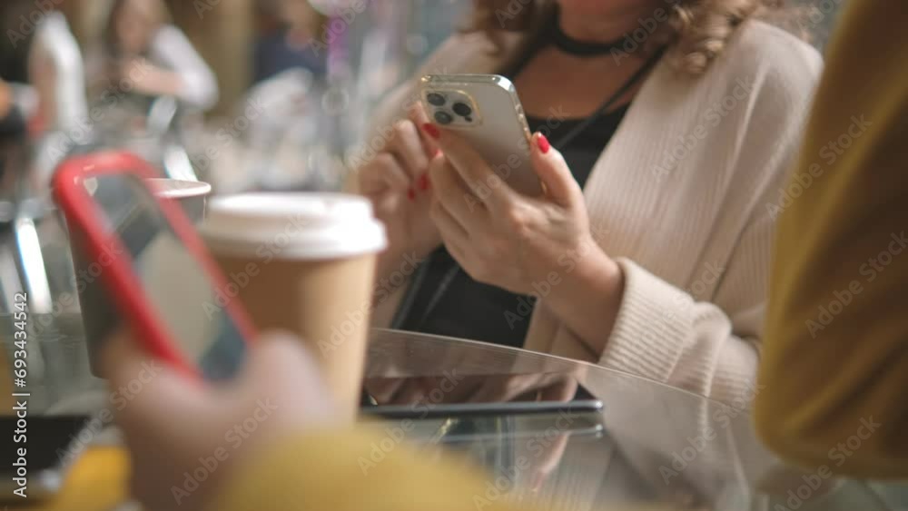 Two women looking at mobile phone indoor. Female friends scroll down ...