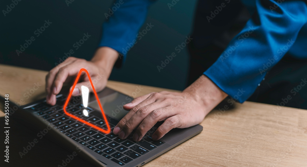 Foto de Businessman using computer laptop with triangle caution warning ...