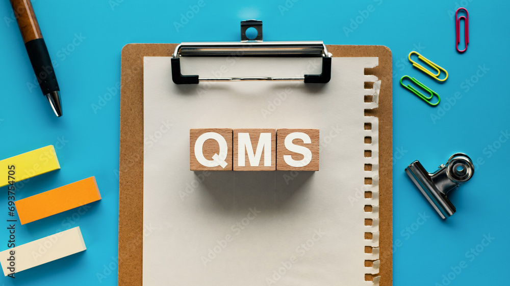 Foto de There is wood cube with the word QMS. It is an abbreviation for ...