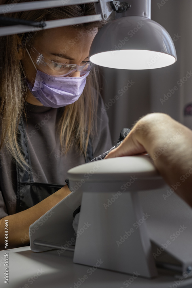 Manicurist at work. Professional manicurist removes old worn nail ...