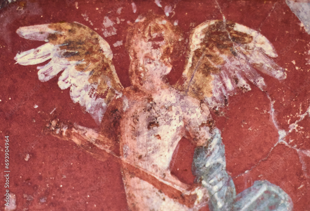 Fresco winged cupid on red background in a Domus of the ancient Pompeii ...