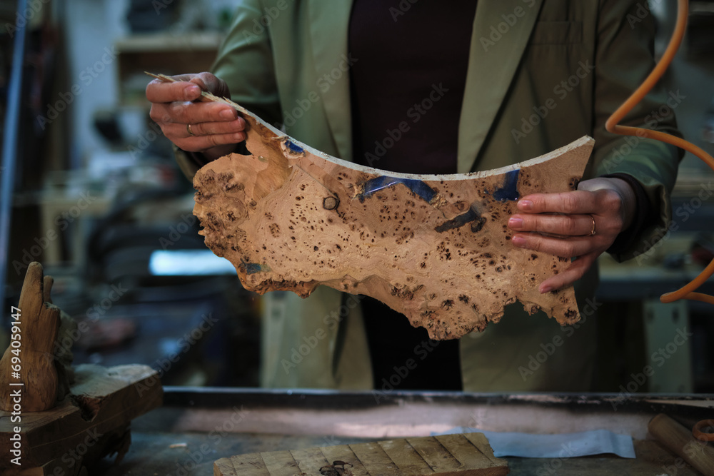 Hands hold a slab of burl wood with intricate grain, highlighting the ...