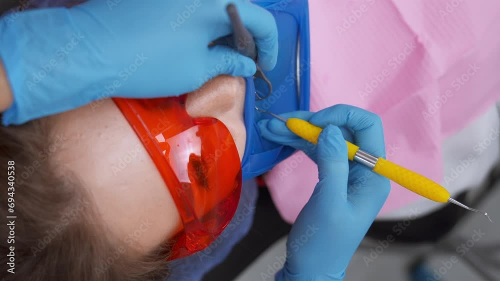 Dentist's hands in gloves with dental punch and cofferdam scarf ...