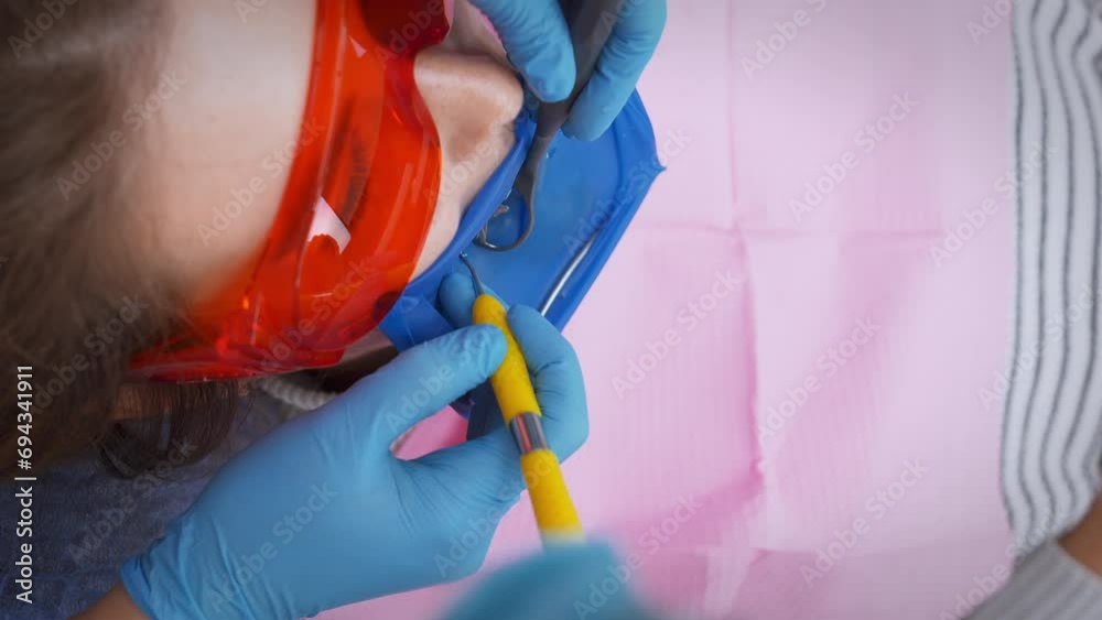 Dentist's hands in gloves with dental punch and cofferdam scarf ...
