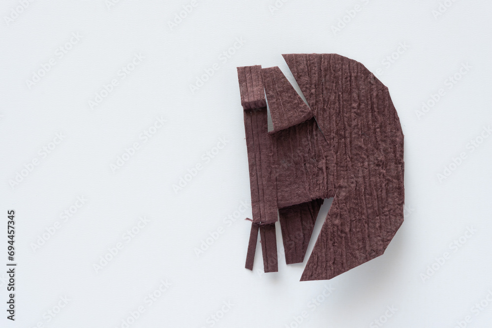 brown paper shape with roundish edges and cut elements on blank paper ...
