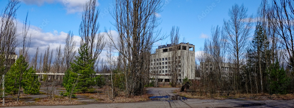A dilapidated building with broken windows, surrounded by overgrown ...