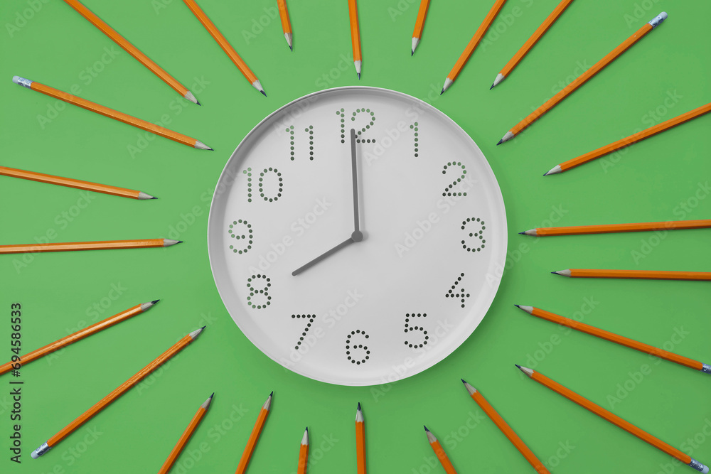 School time. 8 o'clock. Clock and pencils in form of sun rays on green ...