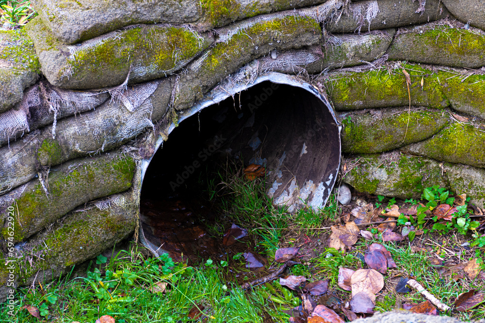 An abstract image of a metal culvert drainage system and stacked sand ...