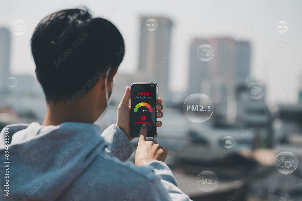 Asian man using a smartphone scanning the weather over smog city from PM2.5 dust. View of ...