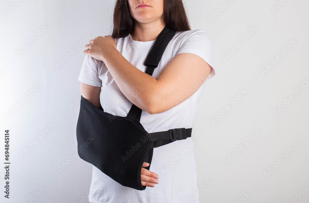 A girl on a white background with a black supporting medical bandage ...