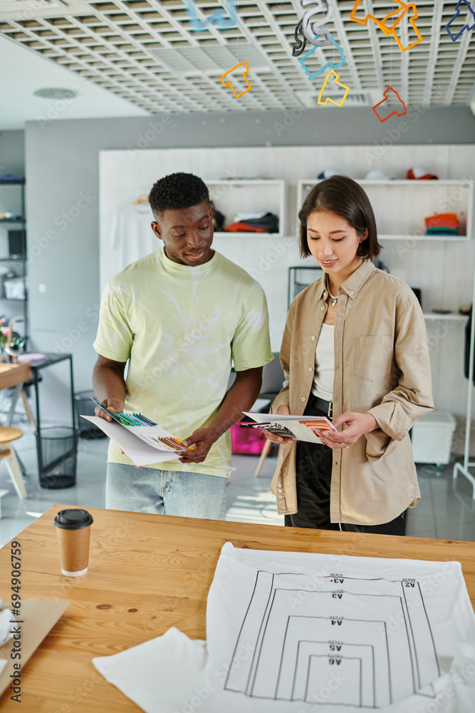 young multicultural designers working with color palette near clothes ...