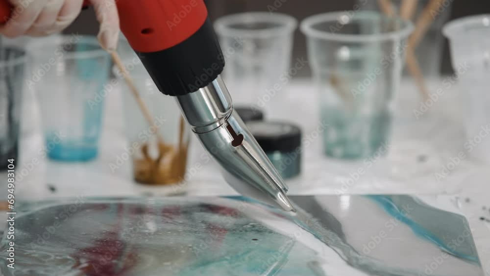 Close-up female artist using construction thermal dryer blowing hot air ...