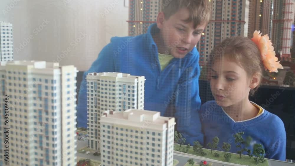 Talking boy and girl look at layout of buildings through glass Stock ...