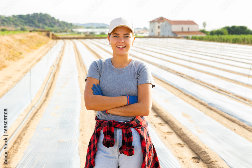 Smiling young girl farm worker standing against background of farm ...