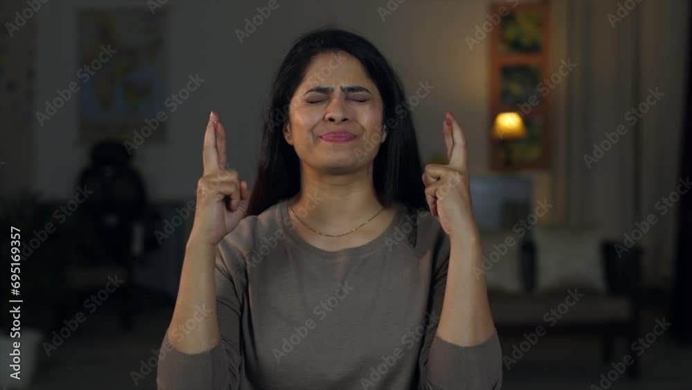 A young female crosses her fingers with a pleading expression on her ...
