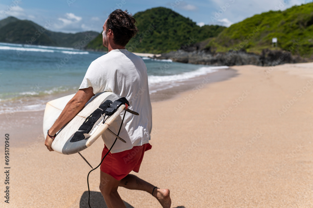 Excited surfer runs into the waves with his shortboard, Indonesia, Asia ...