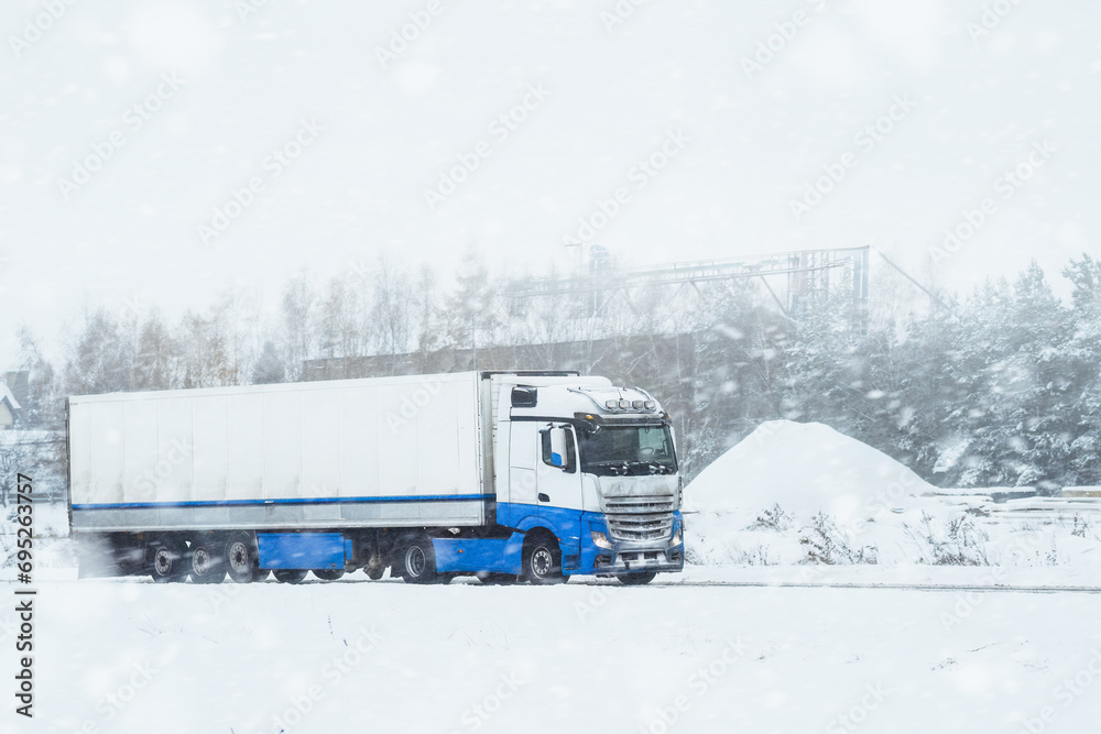 Snowy road trip for a semi-truck. The photo captures a big industrial ...