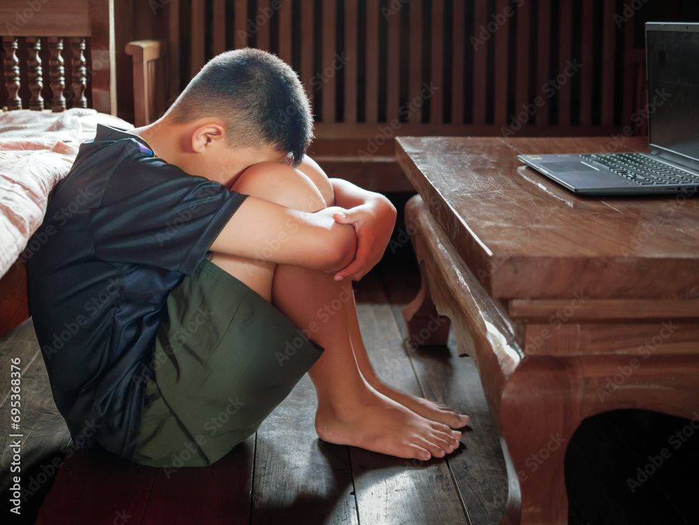 Asian kid boy Upset, sitting in the dark, thinking about conflicts ...