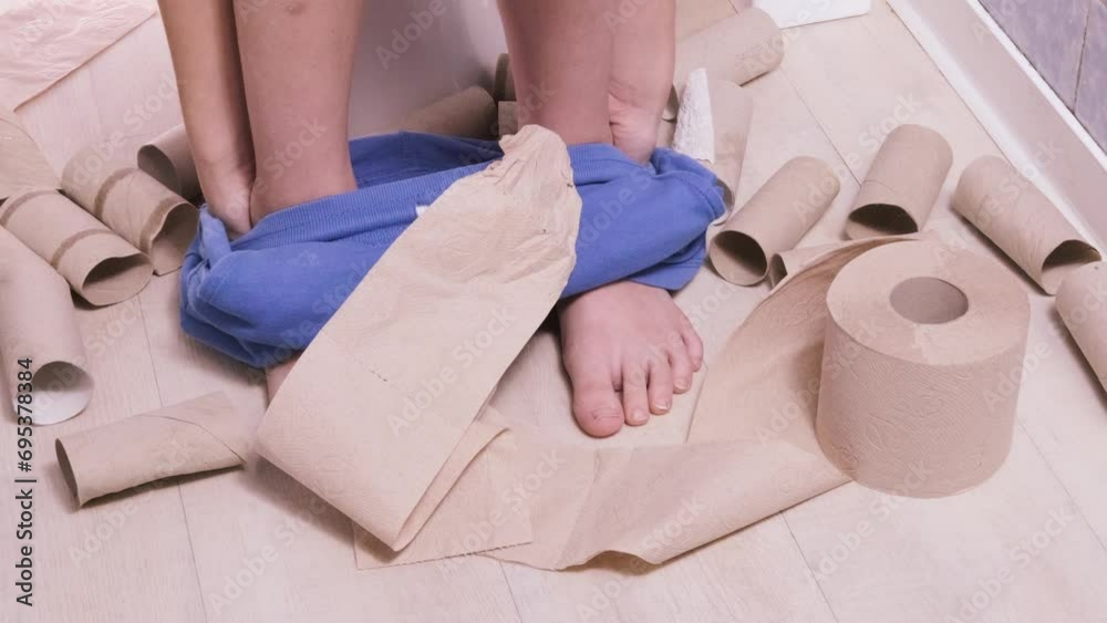 child, boy sitting on the toilet with toilet paper and suffering from ...