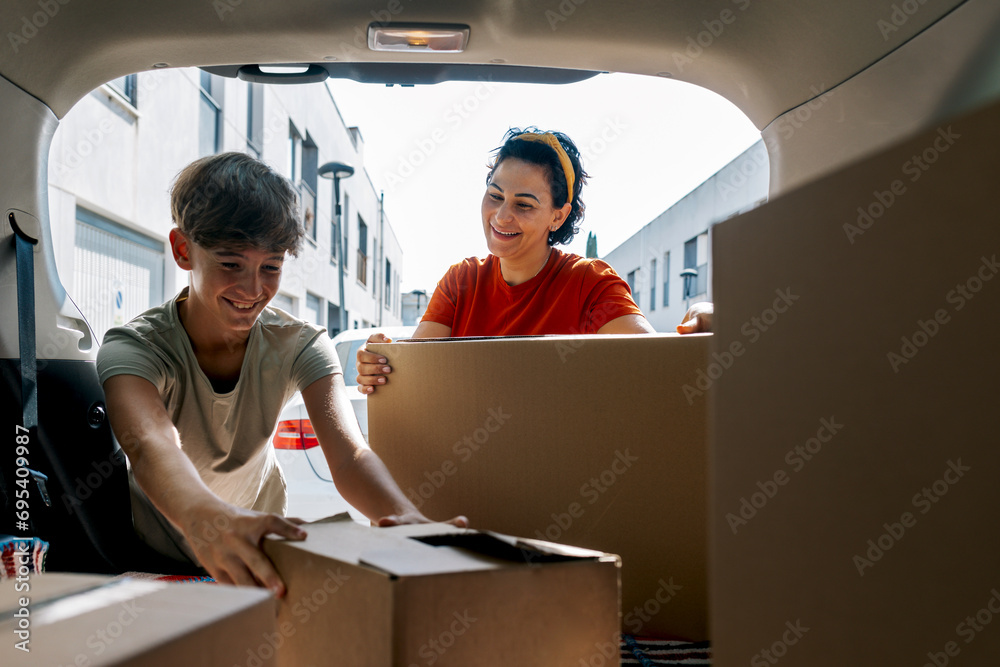 Smiling mother and son picking boxes from car during relocation Stock ...