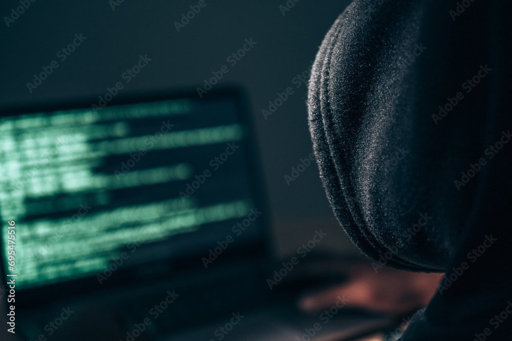 Behind the scenes of an anonymous hacker wearing a hoodie over his head ...