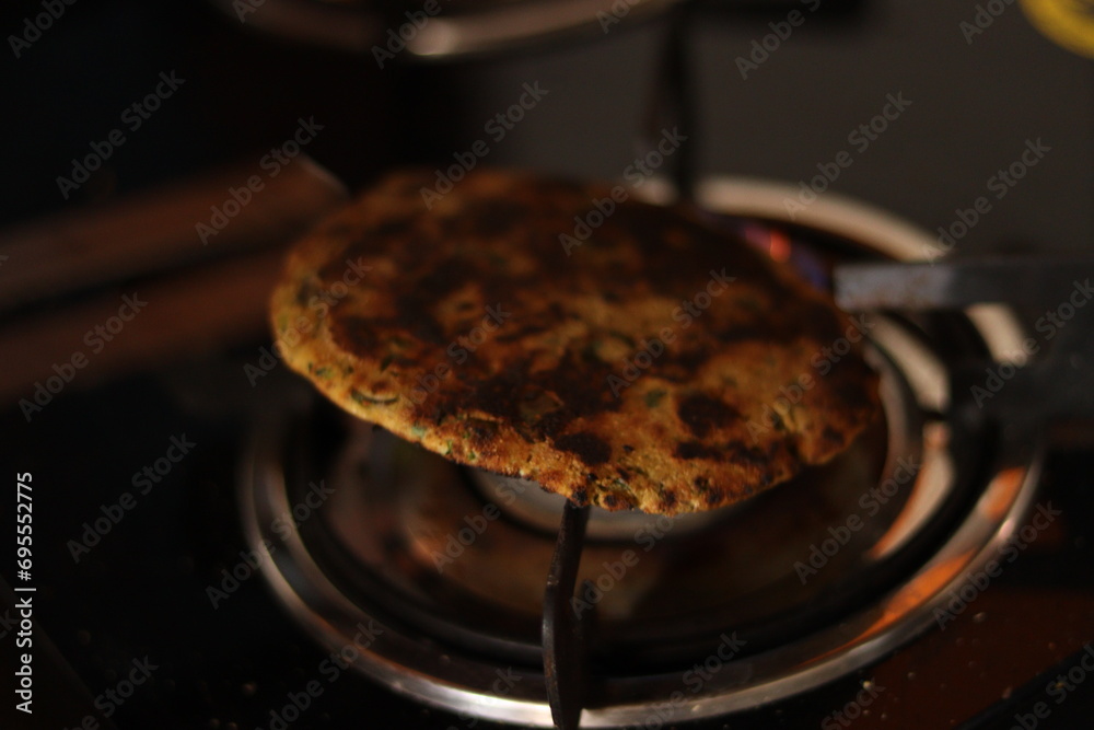 Makka ki roti or corn chapati being cooked on gas stove in Indian ...