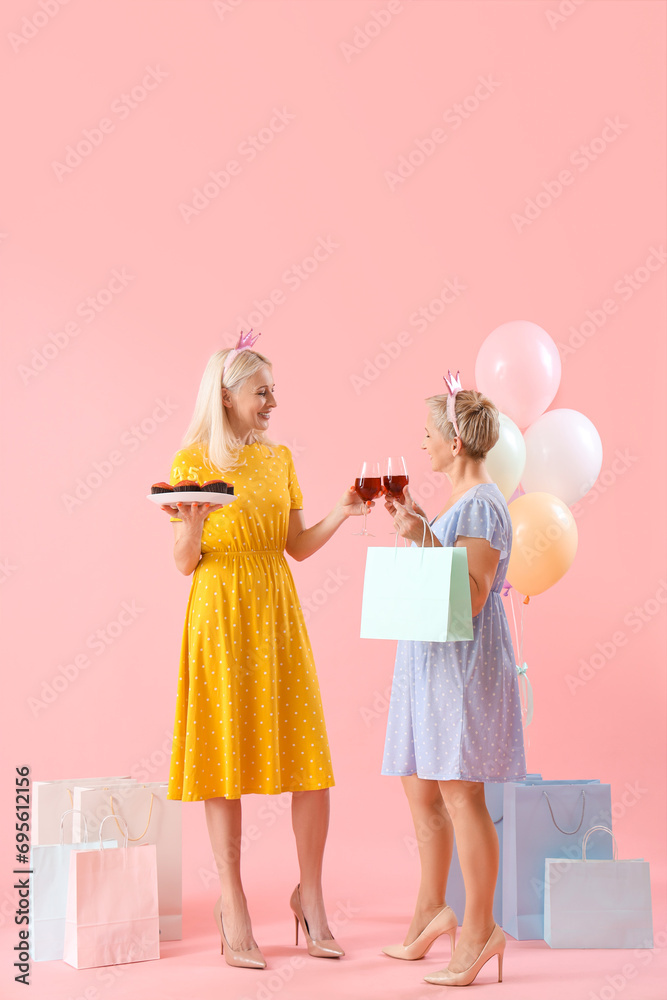 Mature women with muffins and wine celebrating Birthday on pink ...