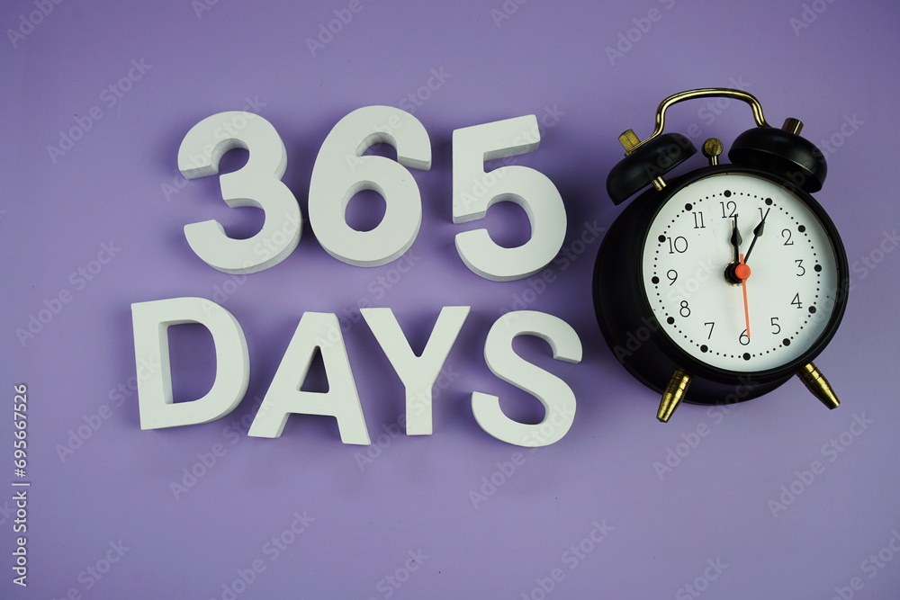 365 Days alphabet letters with alarm clock top view on purple ...