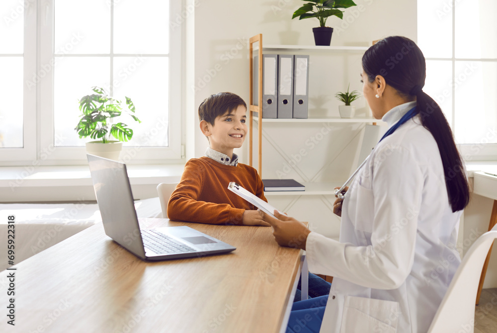 Portrait of a friendly smiling female child doctor pediatrician showing ...