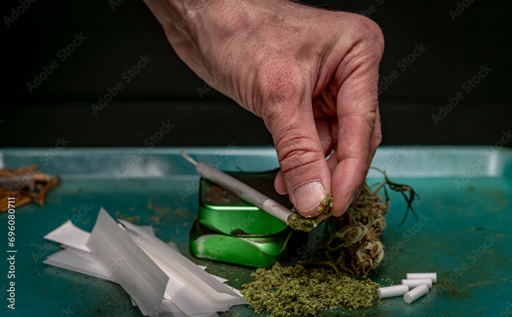 Rolling papers with green dry weed and joint with metallic grinder and ...