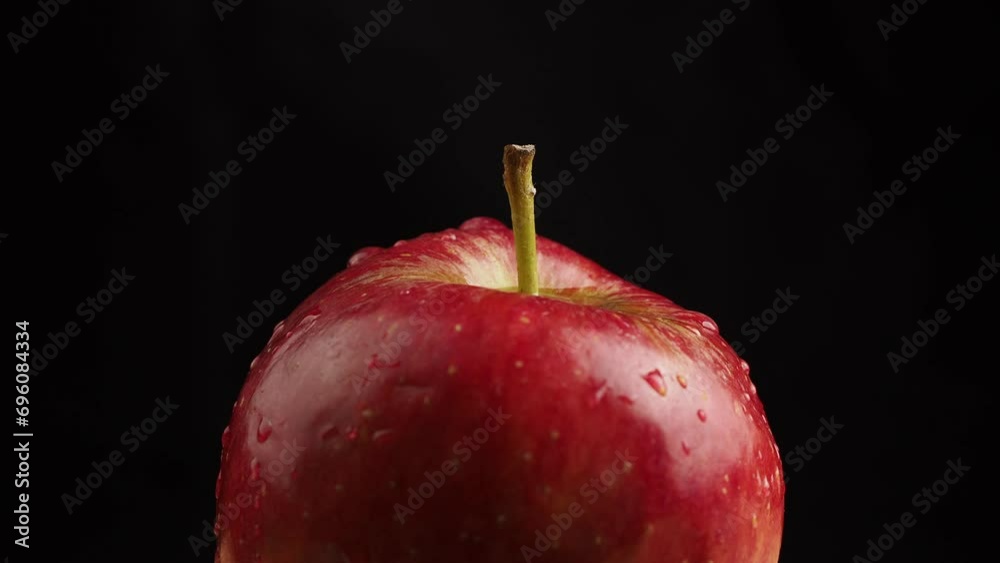 Rotation of a ripe apple in drops of water on a black background. Apple ...