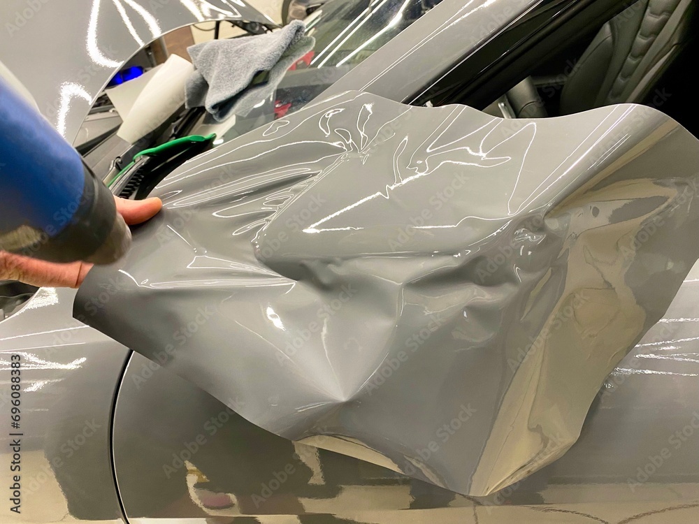 The process of wrapping vinyl film on the side mirror of a car in close ...