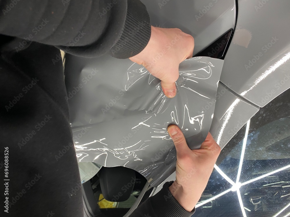 The process of wrapping vinyl film on the side mirror of a car in close ...